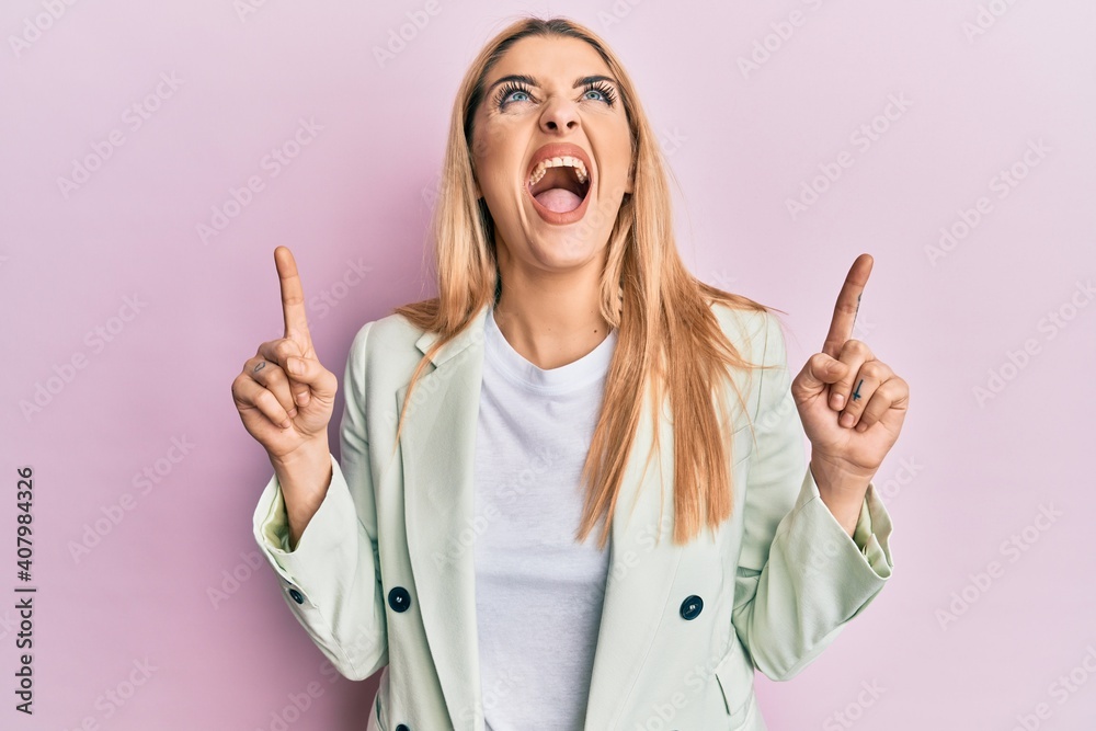 Young caucasian woman wearing business clothes pointing up with fingers ...