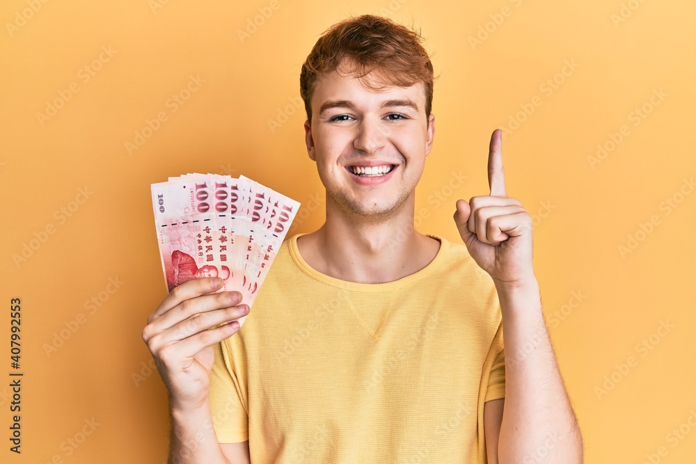 Young caucasian man holding 100 new taiwan dollars banknotes smiling ...