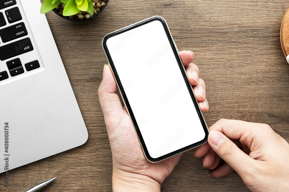 Hand holding smartphone with white blank mock up screen over wood ...