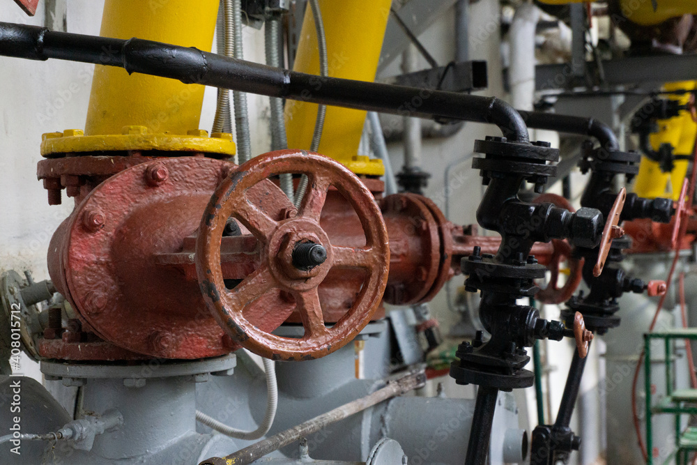 Old valves in the boiler room. Pipe gate valve close up. Lots of pipes ...