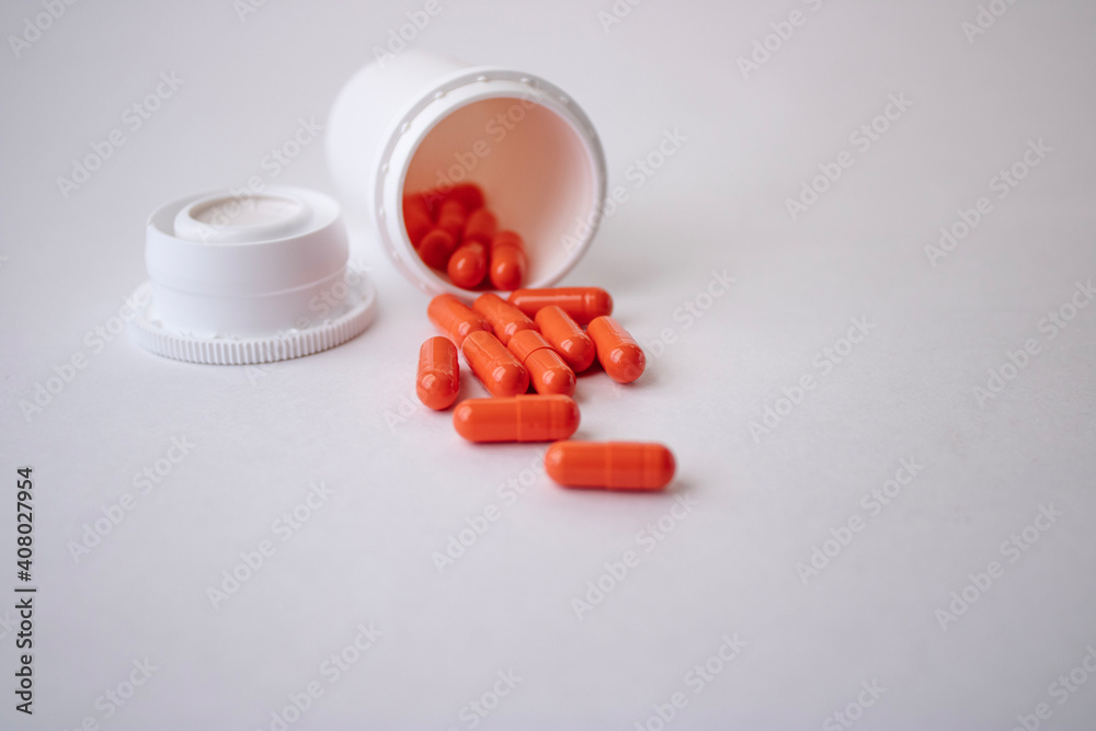 Tablets capsules of orange color on a white background dropped out of a ...