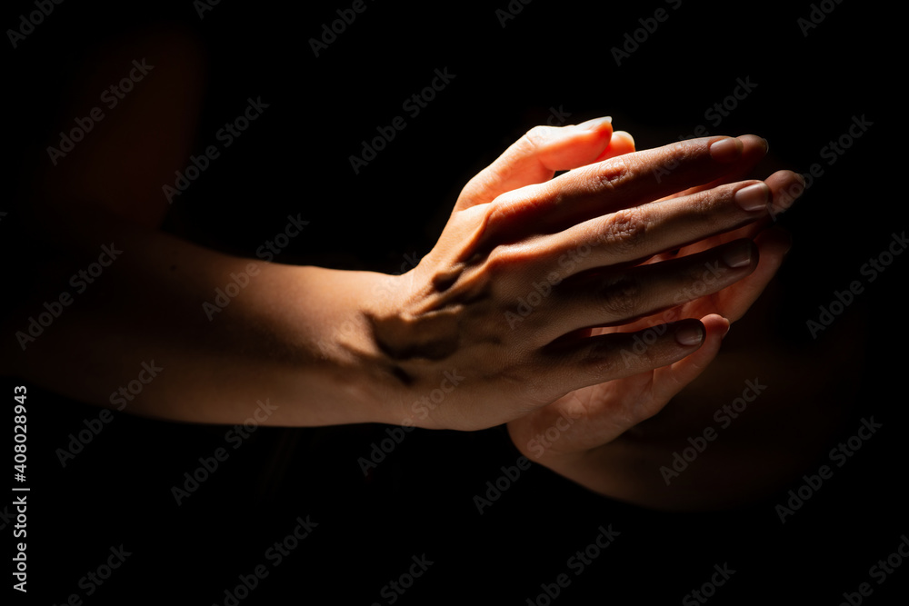 Praying hands on a black background. Light from above. Hands folded in ...