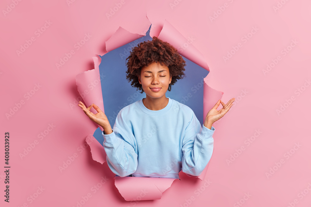 Calm peaceful dark skinned young woman shows okay or zen gesture ...