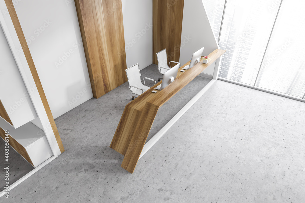 Top view of white and wooden reception desk with computers near window ...