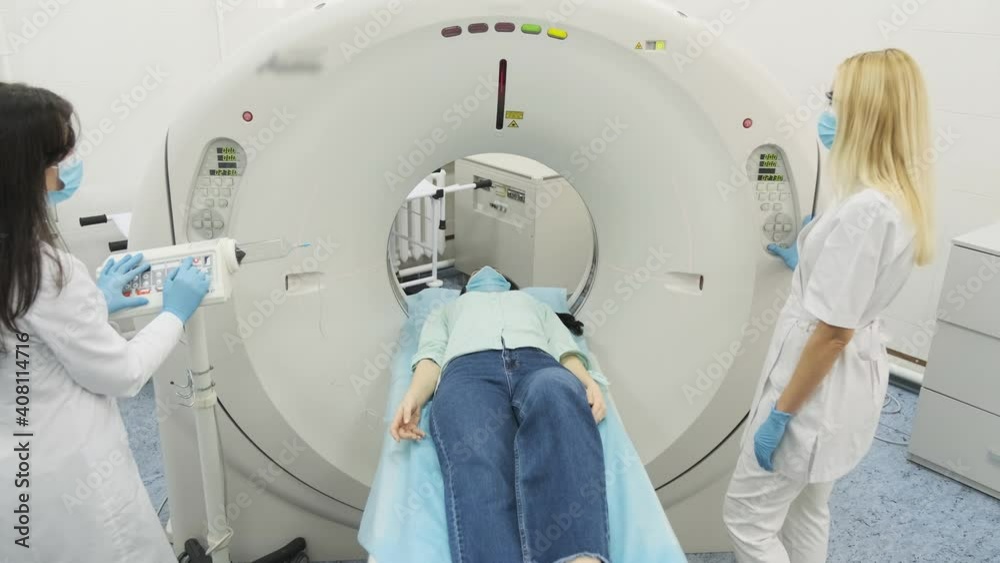 Female patient is undergoing CT or MRI scan under supervision of two ...