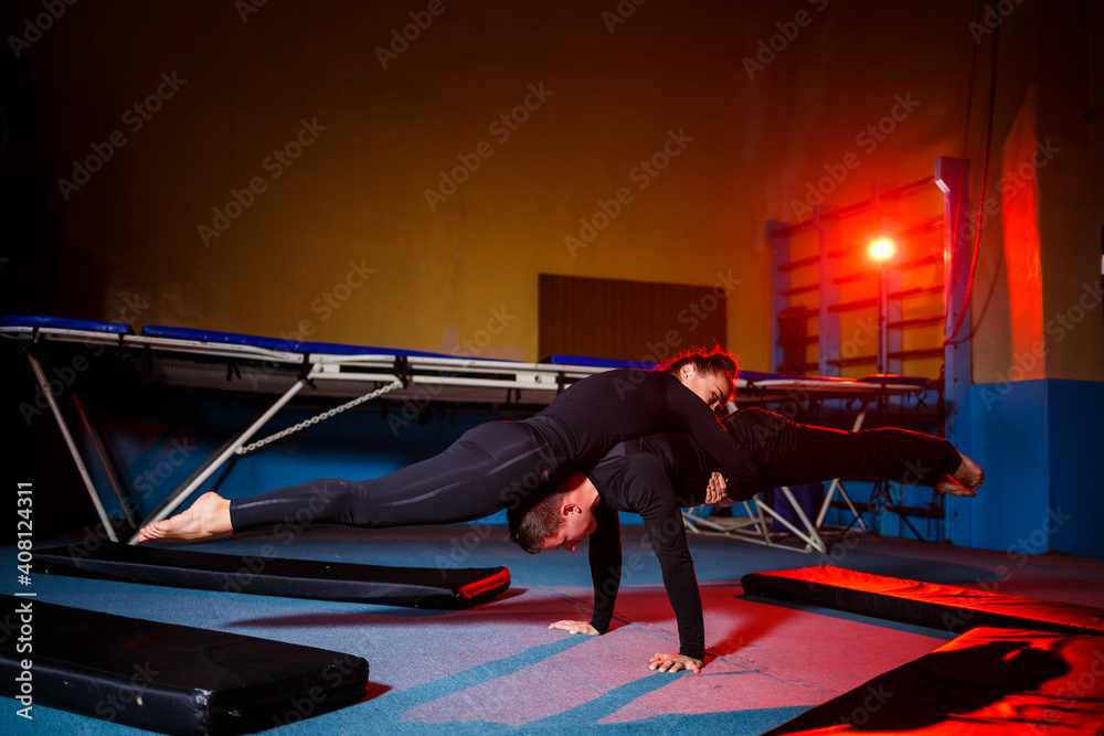 Young woman and man gymnasts do acrobatic exercises in the gym. Sports ...