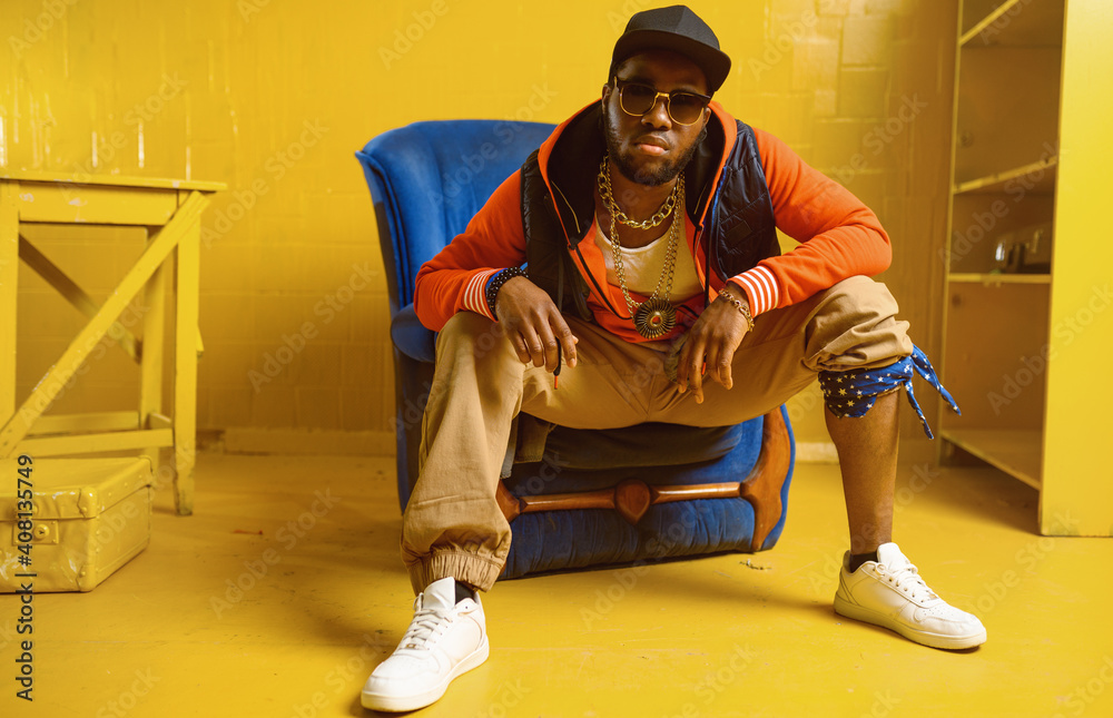 Rapper posing in chair in studio with yellow tones Stock Photo | Adobe ...