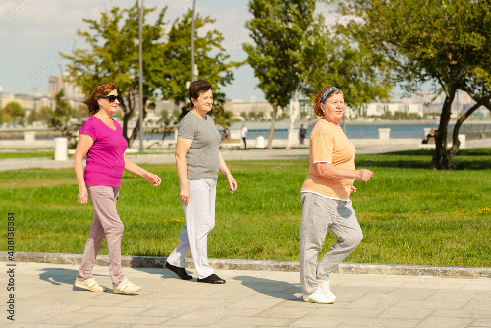 Three women running in a public park, having a healthy lifestyle for ...