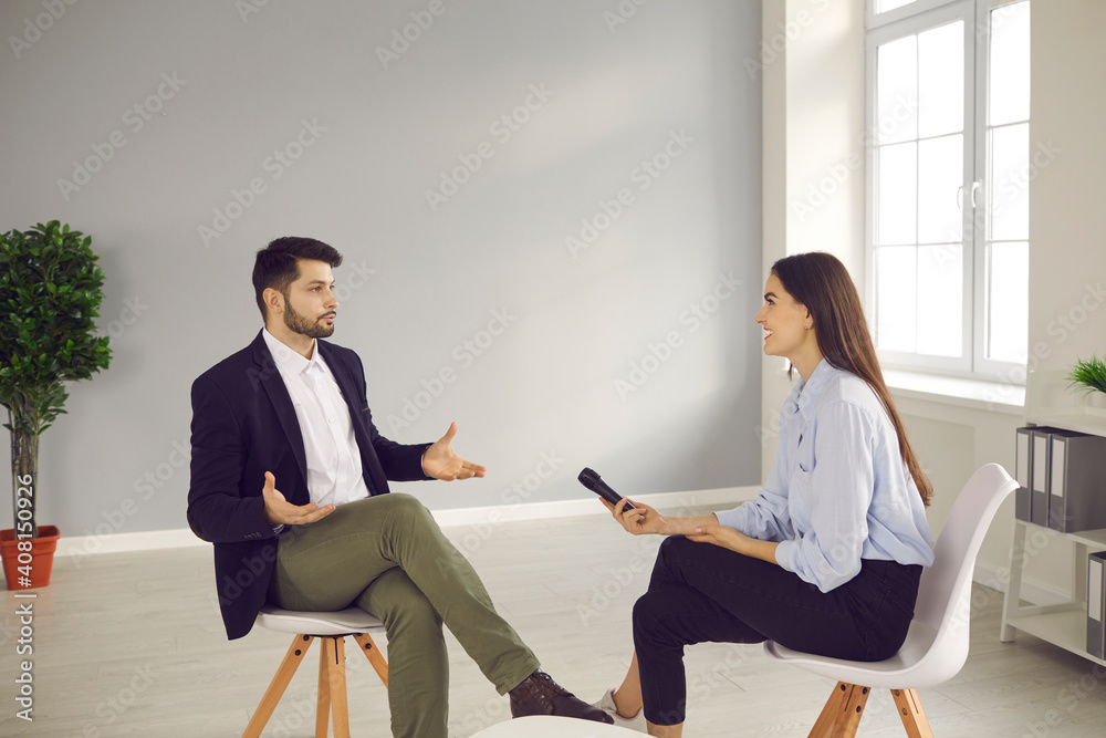 Fotka „Young man sitting on chair in television studio and giving ...