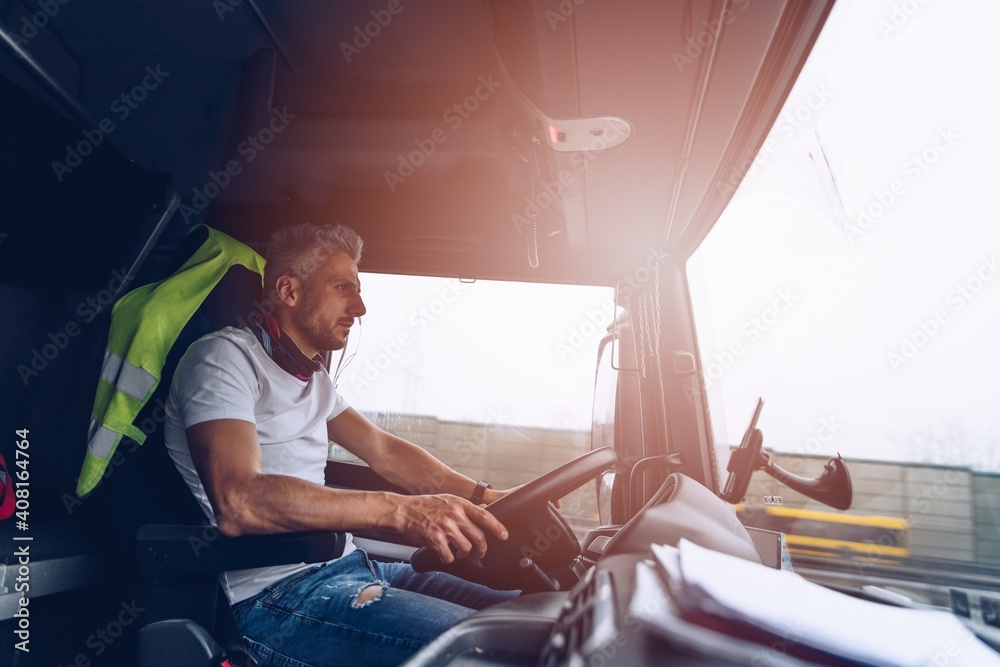Handsome driver at the wheel of a truck at work. Semi Truck Driver Job ...