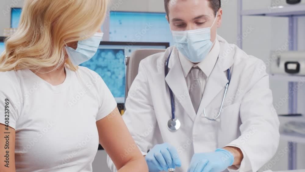 Doctor makes a coronavirus vaccine using a syringe and hypodermic needle. Professional medical ...