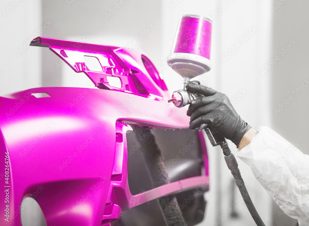 Professional male car painter is painting in garage by airbrush. Man ...