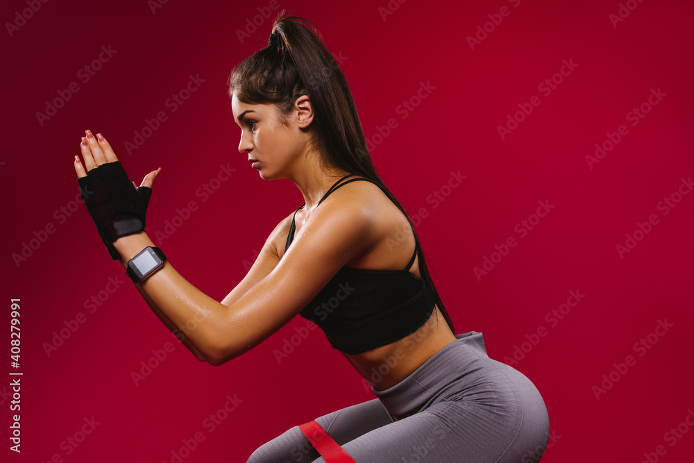 Focused girl with a fitness rubber band shakes her muscles and looks to ...