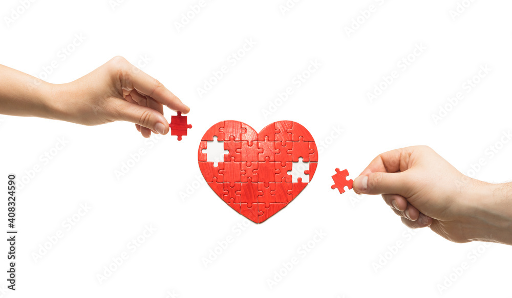 Two people put together a heart-shaped puzzle. The concept of building ...
