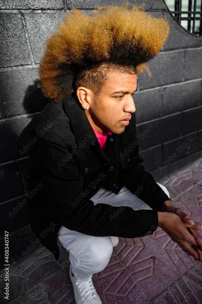 Hombre joven latino, moreno con pelo rizado a lo afro sentado en un ...