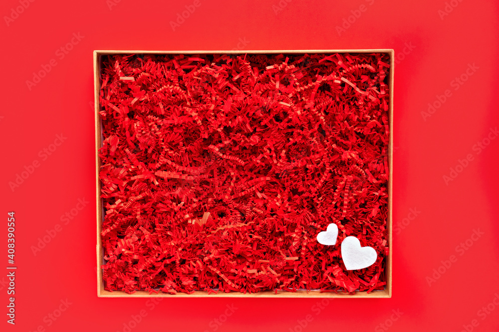 Opened gift box with shredded paper on wooden background. Red paper box ...