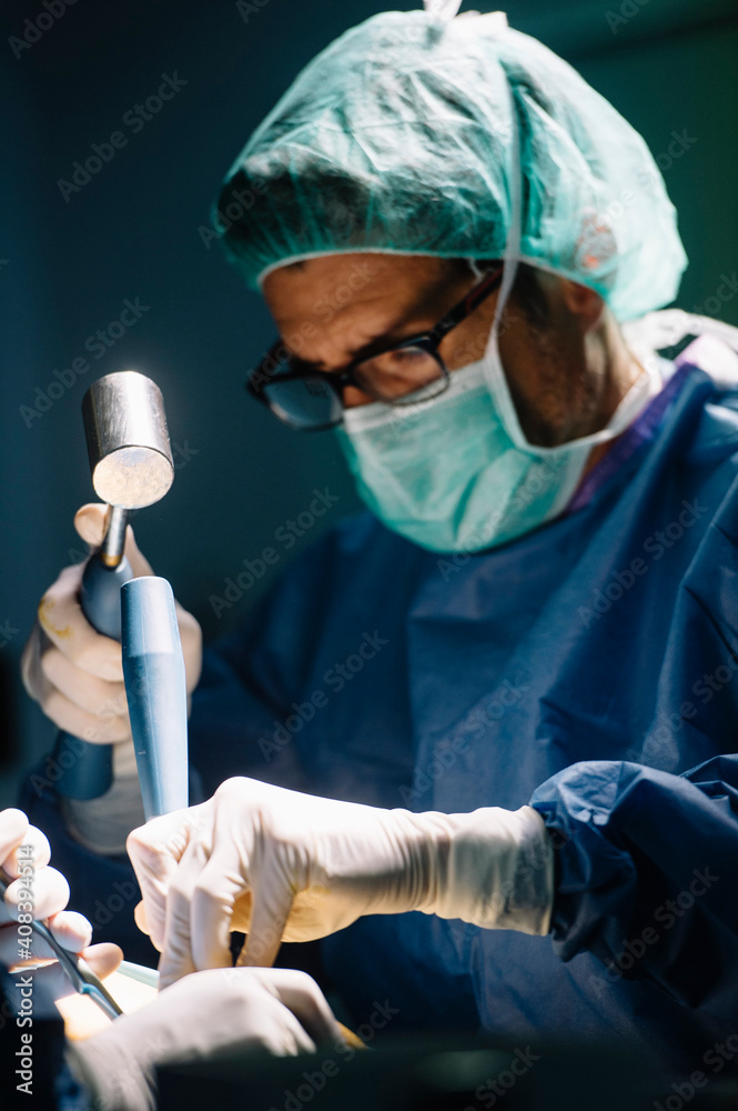 Male surgeon using hammer while doing ankle surgery in operating room ...