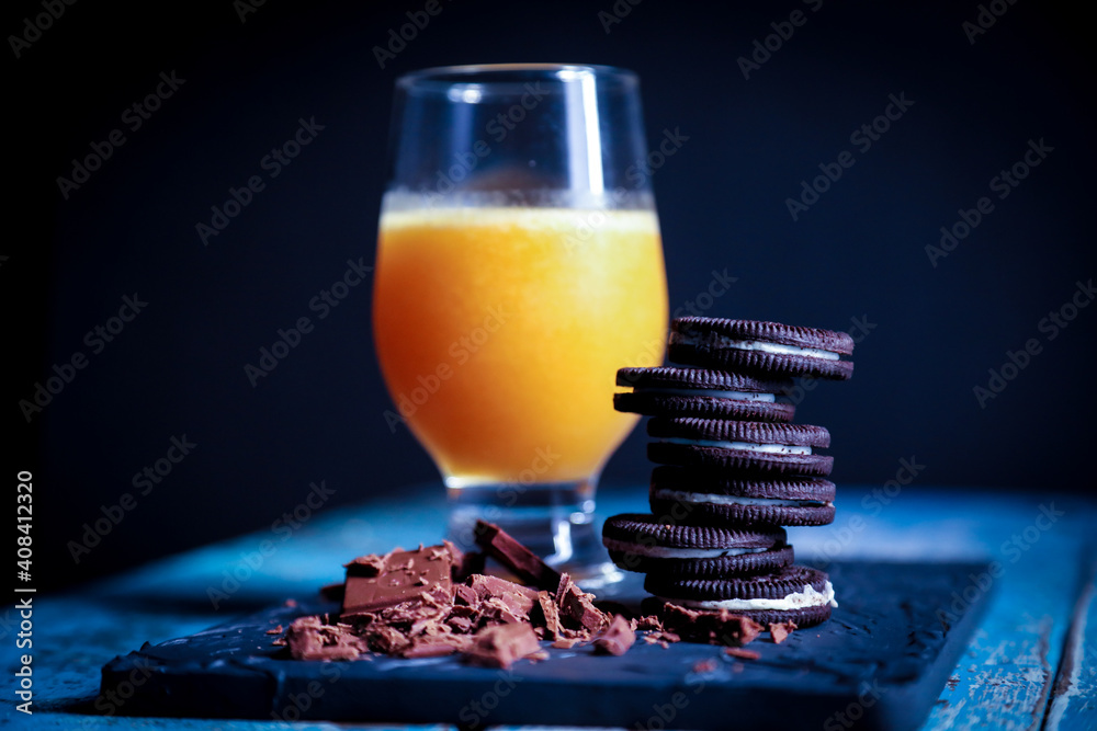 Biscoito de chocolate com suco de laranja em mesa de madeira azul com ...