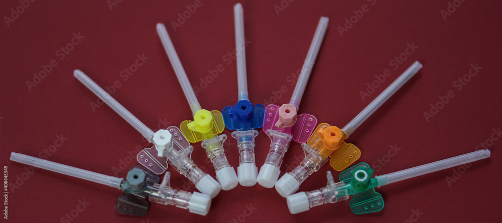intravenous catheters on a red background, shot close-up. multicolored ...