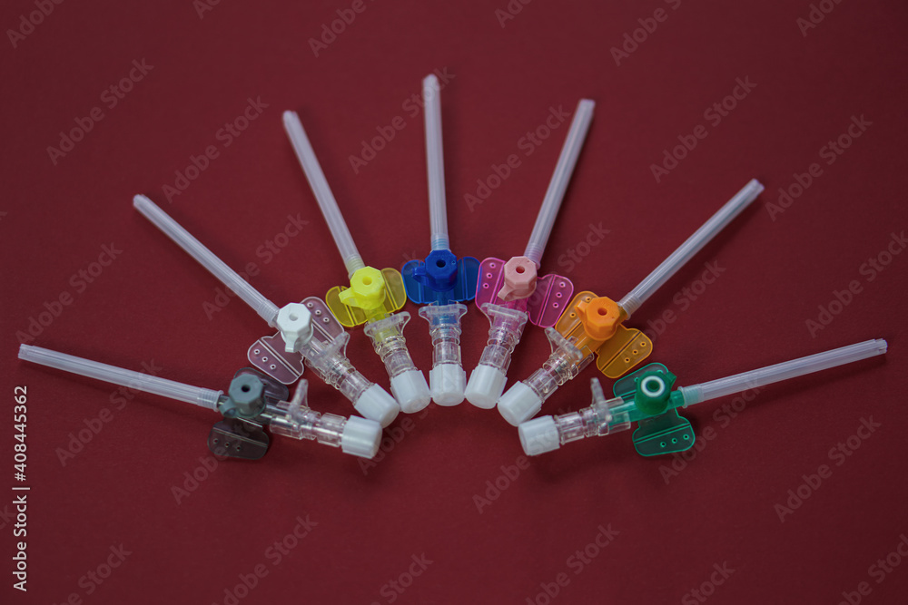 intravenous catheters on a red background, shot close-up. multicolored ...
