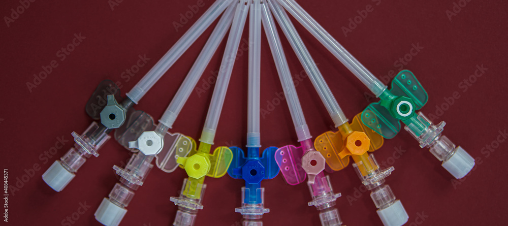intravenous catheters on a red background, shot close-up. multicolored ...