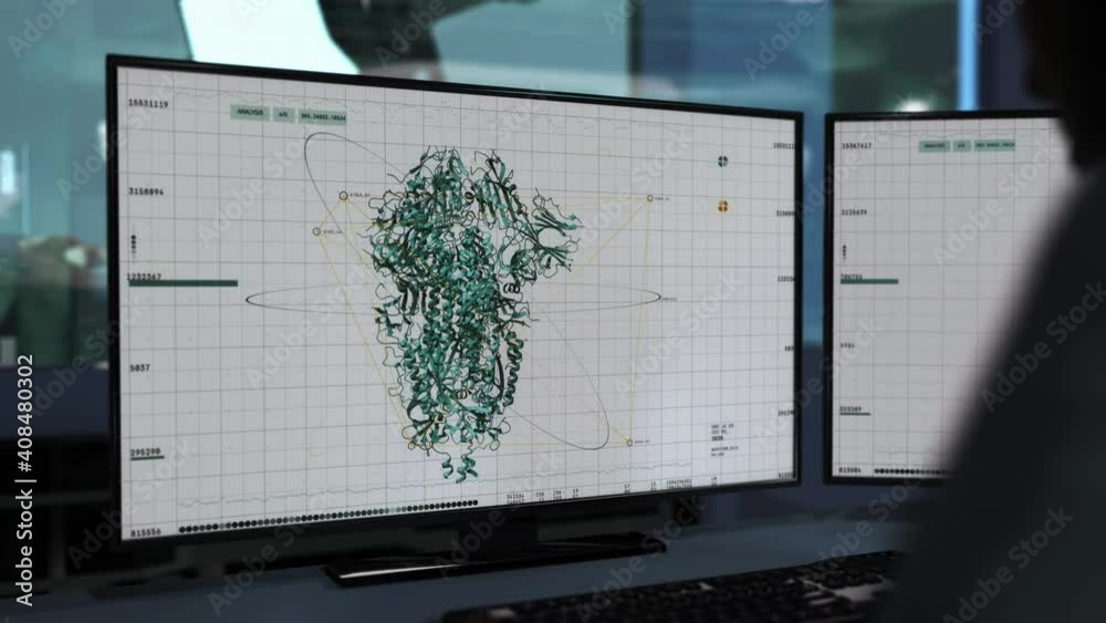 Scientist is sitting in front a computer. Two computer screens and a ...