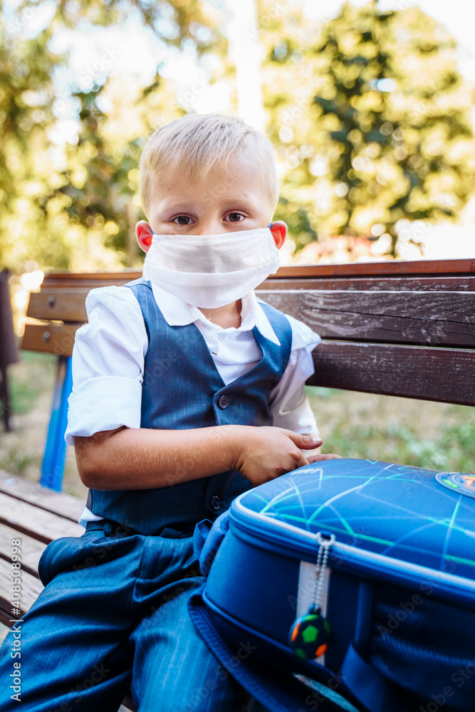 Young student of first grade stands in the schoolyard. Examines items ...