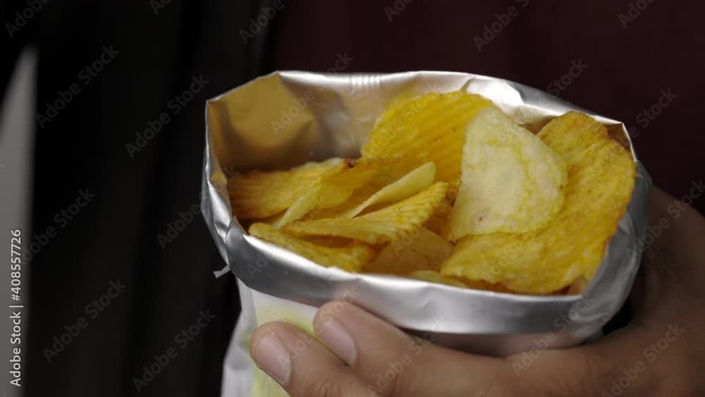 Close up Young man eating Crispy Potato chips salty snacks in paper bag ...