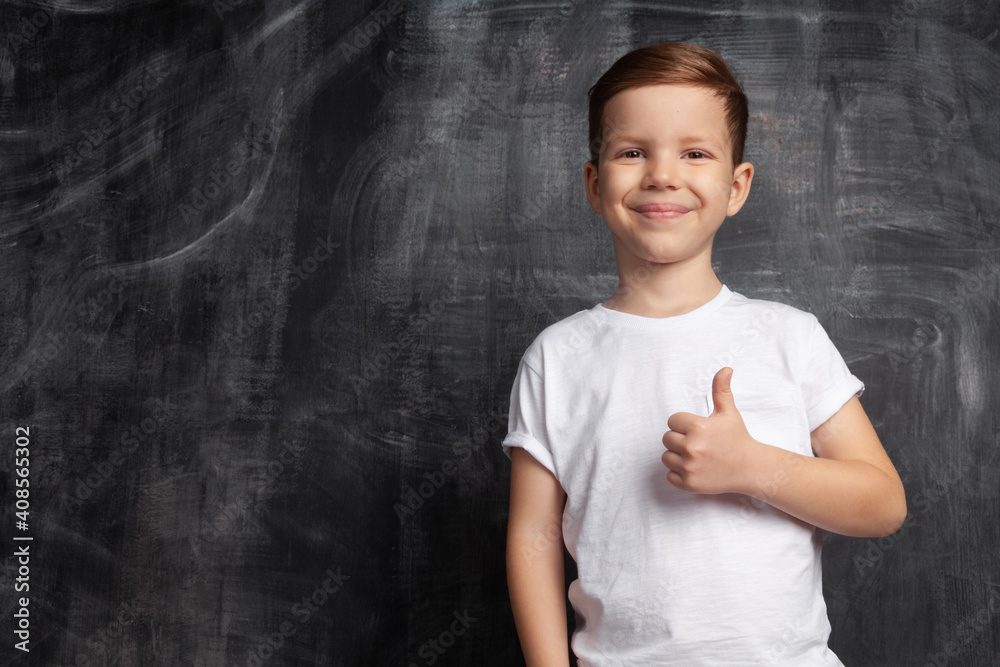 Smiling kid boy showing thumb up gesture or liking on backdrop of black ...