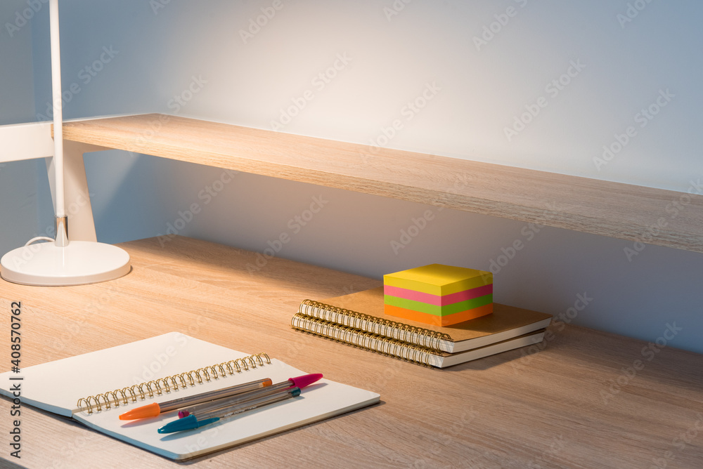 study table with notebooks, pens and notes illuminated with a gooseneck ...
