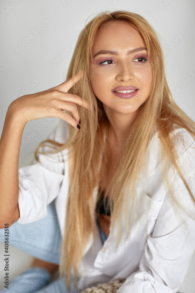 Beautiful Happy Blonde Woman With Long Hair In Jeans And White Shirt Sitting On Floor Stock