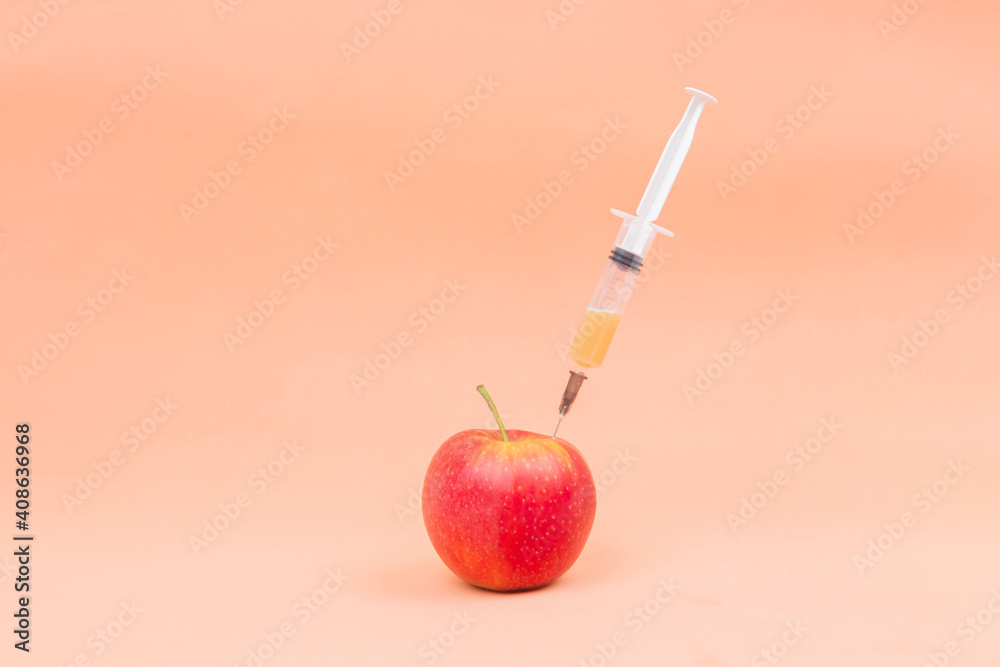 Syringes with different chemicals injections into a red apple on an ...
