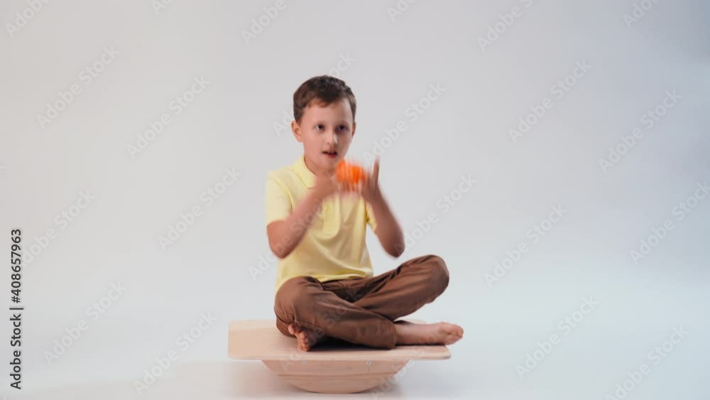 a little boy balancing on the simulator throws up the ball and tries to ...