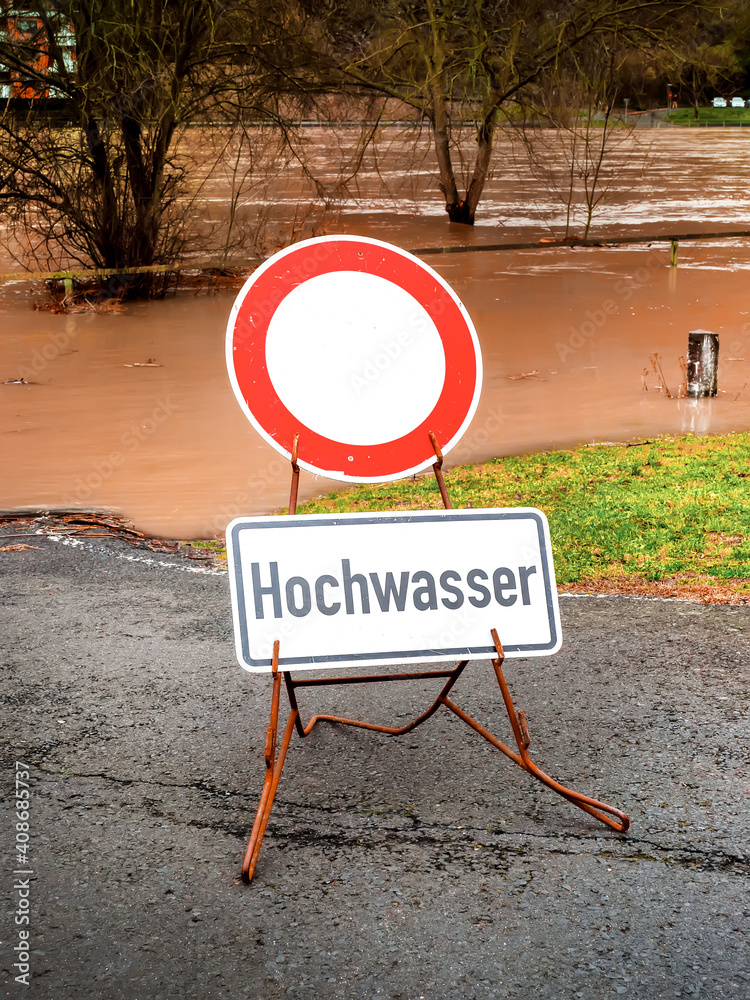 Warning sign with lettering Hochwasser (engl. flood) near the river ...