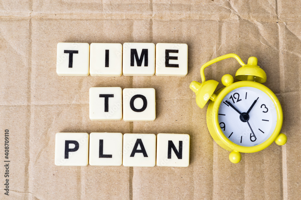 Top view of clock and srabble letters with text TIME TO PLAN over cork ...