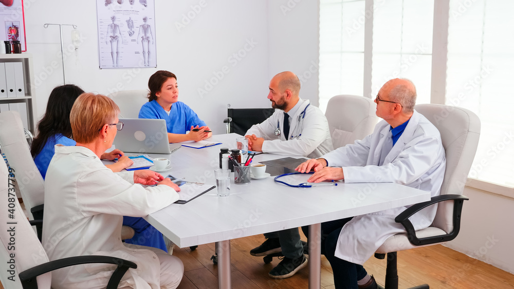 Team of expert doctors sitting at desk in hospital conference room ...
