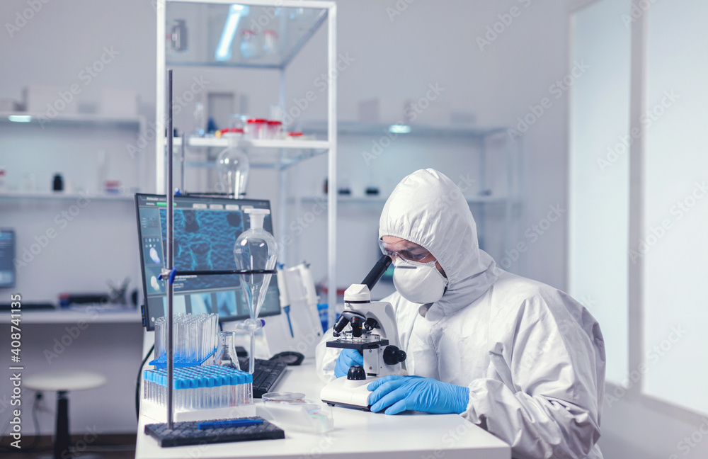 Scientist studying new virus in laborator using microscope dressed in ...