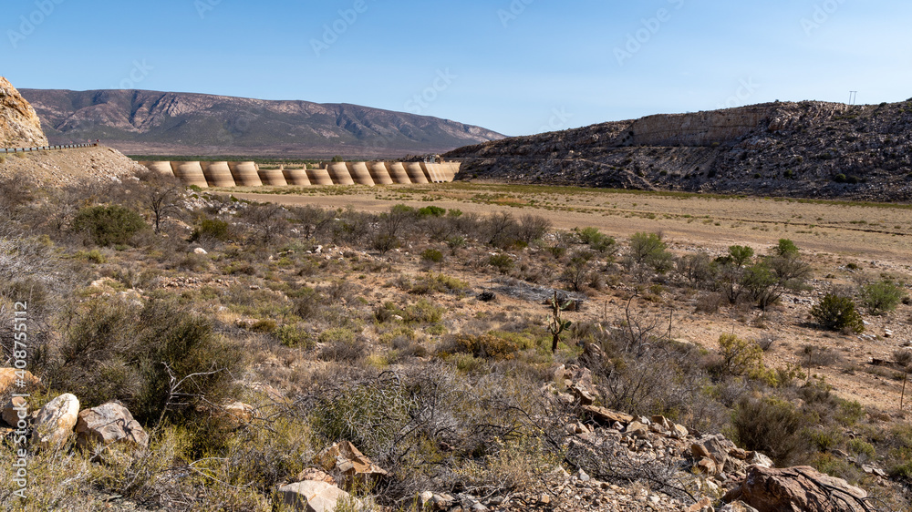 Dry reservoir behind large concrete dam showing the effects of climate ...
