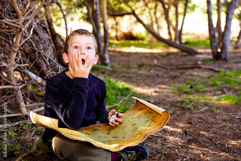 A clever boy searches an ancient map for something buried in a forest ...