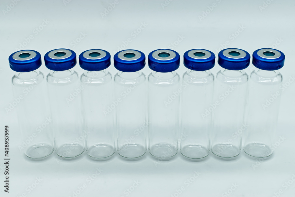 Row of transparent glass medical vials for injection with blue sealed ...