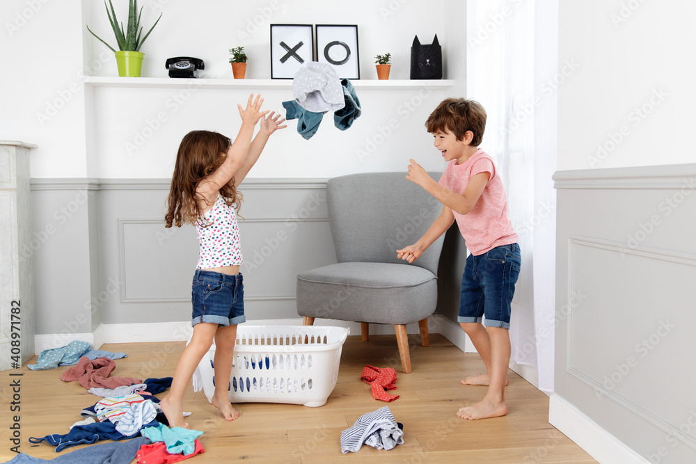Young siblings throwing clothes in the air from laundry basket Stock ...