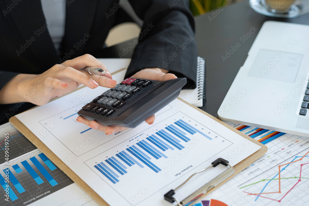 Close-up business women using a calculator and a laptop to calculate ...