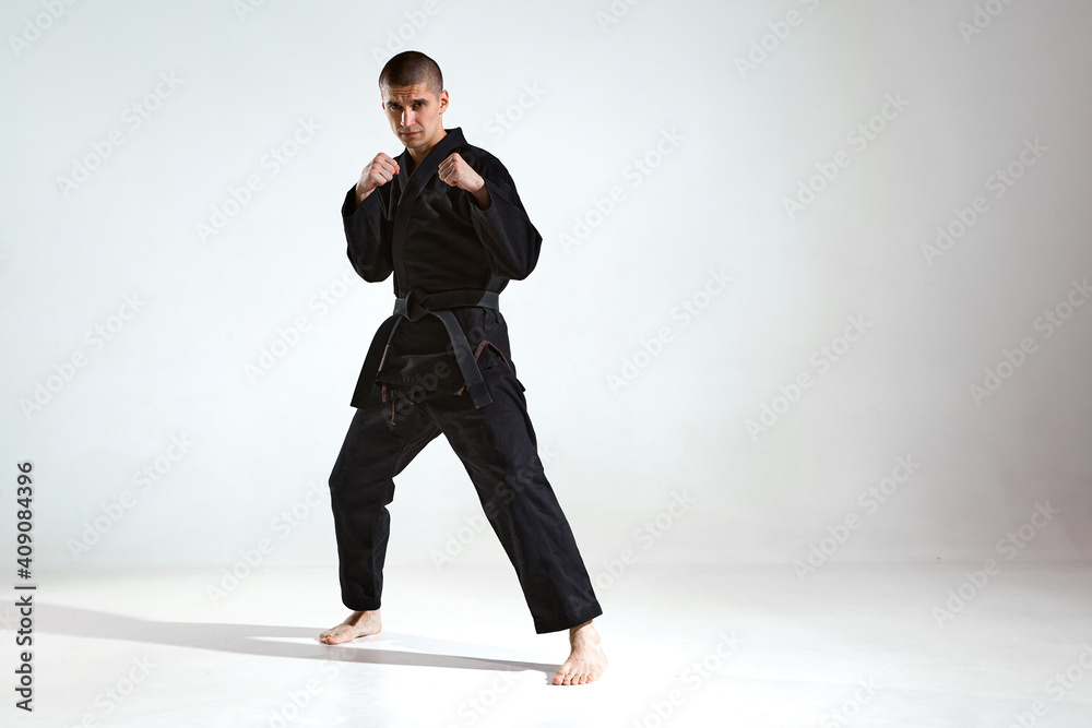 Confident guy in black kimono fighter posing in karate stance on studio ...