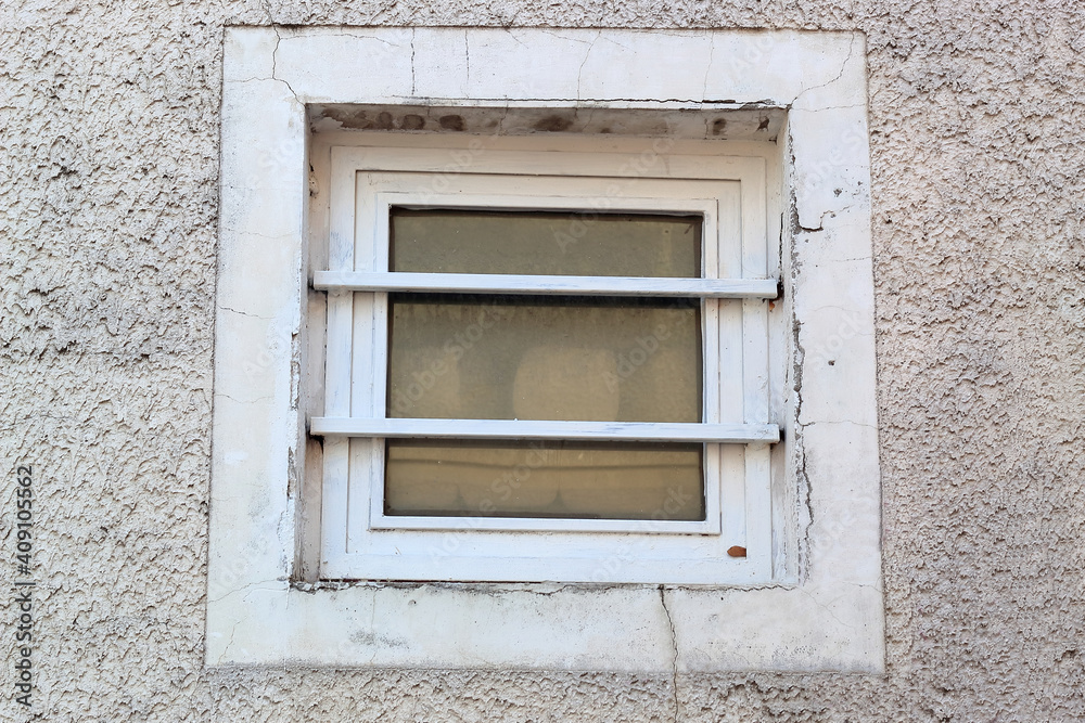 an isolated old white painted wooden frame window with grill on the ...