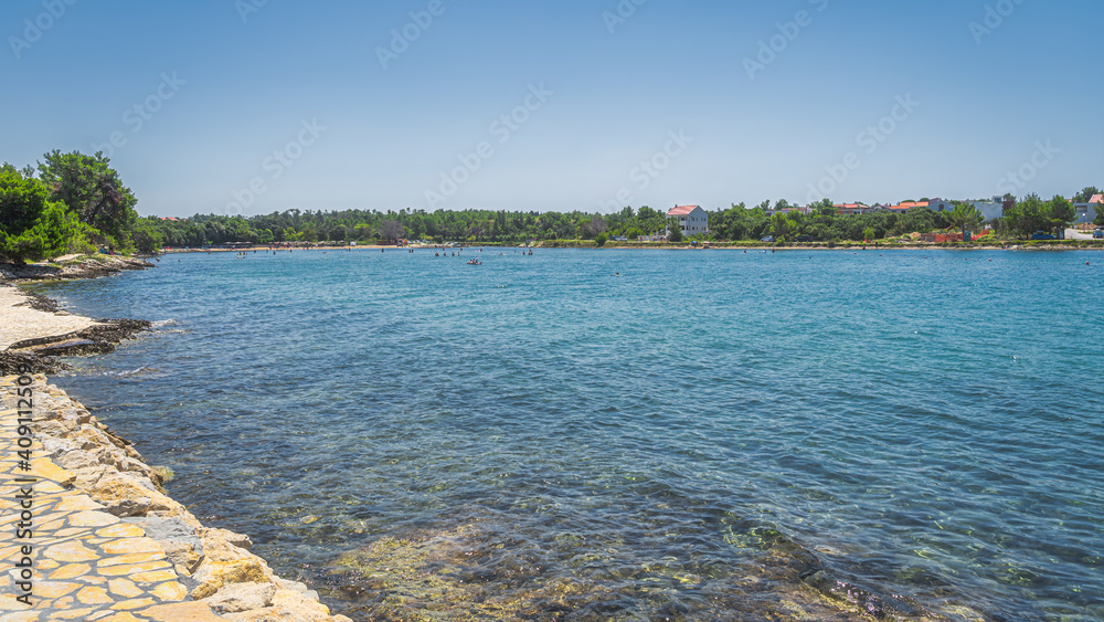 People relaxing in clear waters of Zaton bay with rocky coastline ...