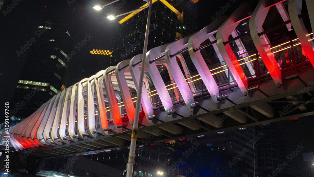 a pedestrian bridge covered in colorful neon lights at night in the ...