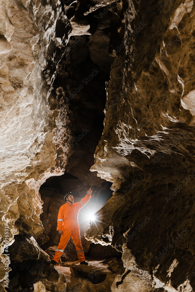 Man walking and exploring dark cave with light headlamp underground ...