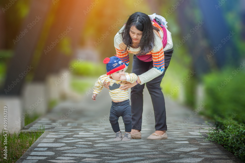Mom teaching her son first baby steps in the park Stock Photo | Adobe Stock