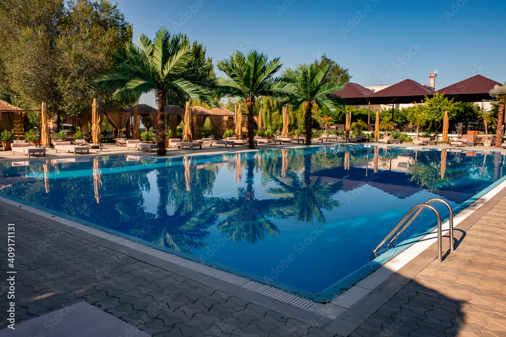Swimming pool at the luxury tropical resort. Swimming pool with the some beach lounges at the ...