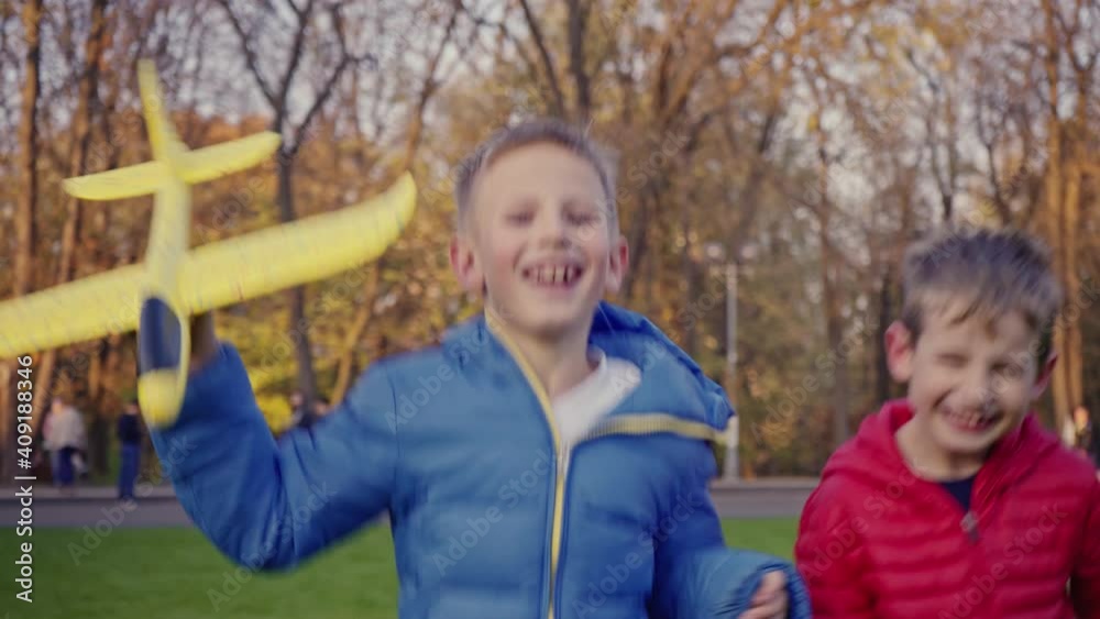 Children launch a yellow toy airplane into the air. Two boys in the ...